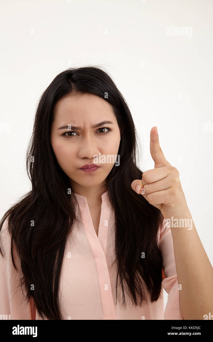 Portrait of a young angry woman pointing finger at camera isolated on a ...