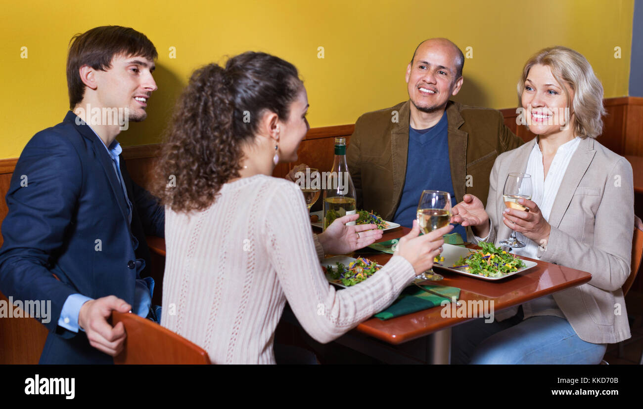 Positive pleasant middle class people enjoying food and wine in cafe ...