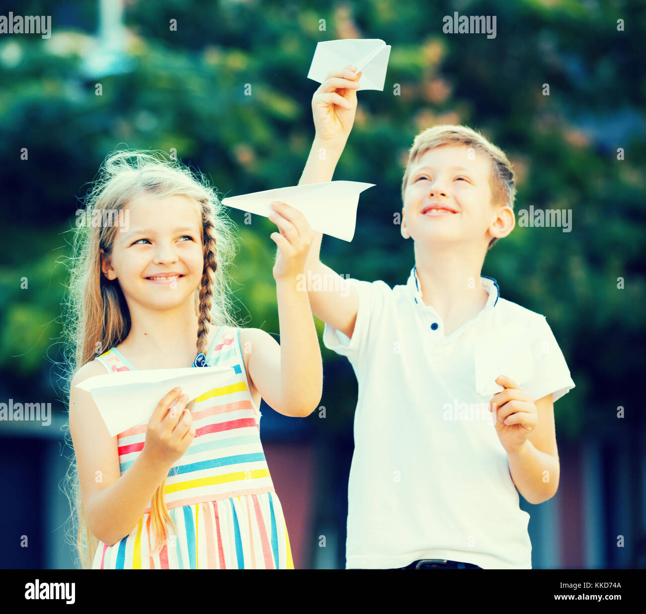 two glad children playing with paper planes in town on summer day Stock ...