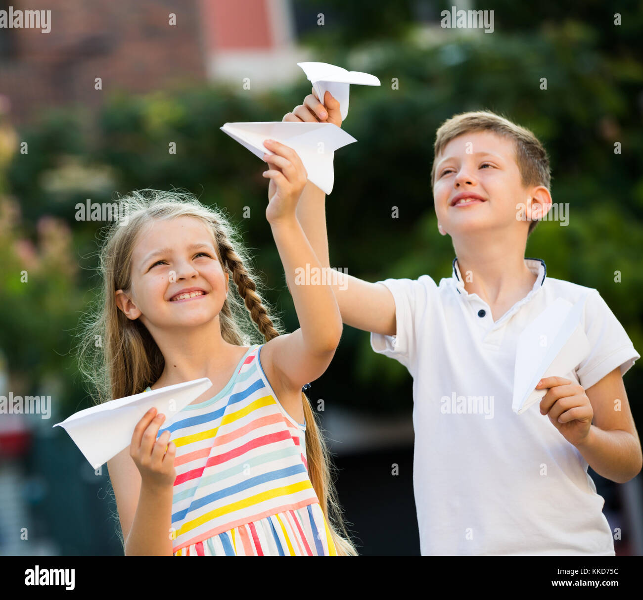 Two smiling kids playing with flying paper planes outdoors Stock Photo ...