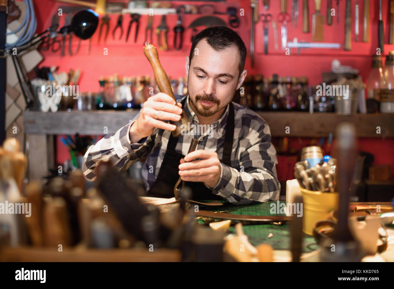 Young diligent male worker working on leather for belt in leather ...