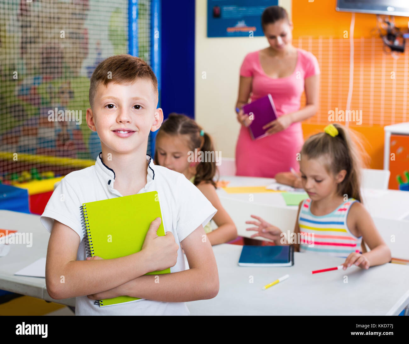 Smiling boy pupil standing in elementary school class with notebook in ...