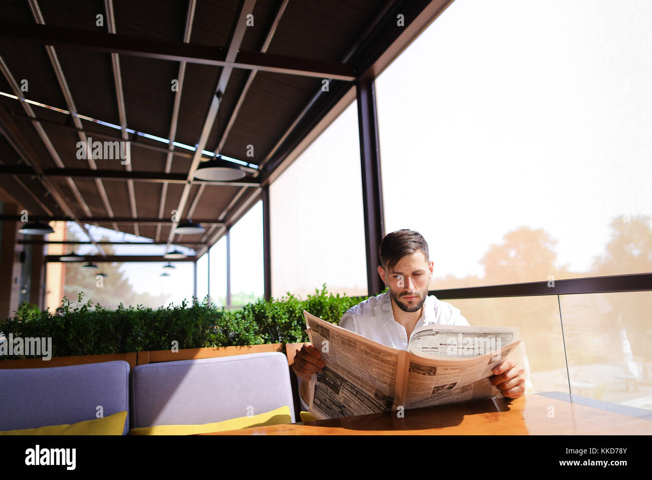 Handsome male person reading newspaper and wondering Stock Photo - Alamy