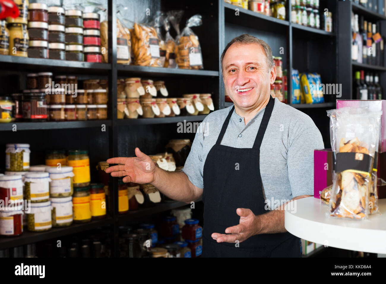 smiling man standing near counter with assortment of grocery products ...