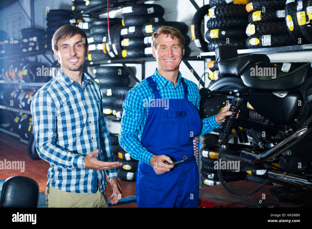 Positive mechanic and happy customer talking about motorbike in ...