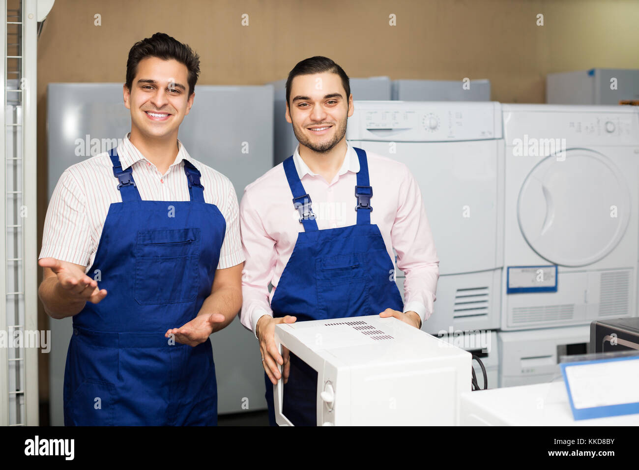 Portrait of smiling workers in uniform working at household appliances ...