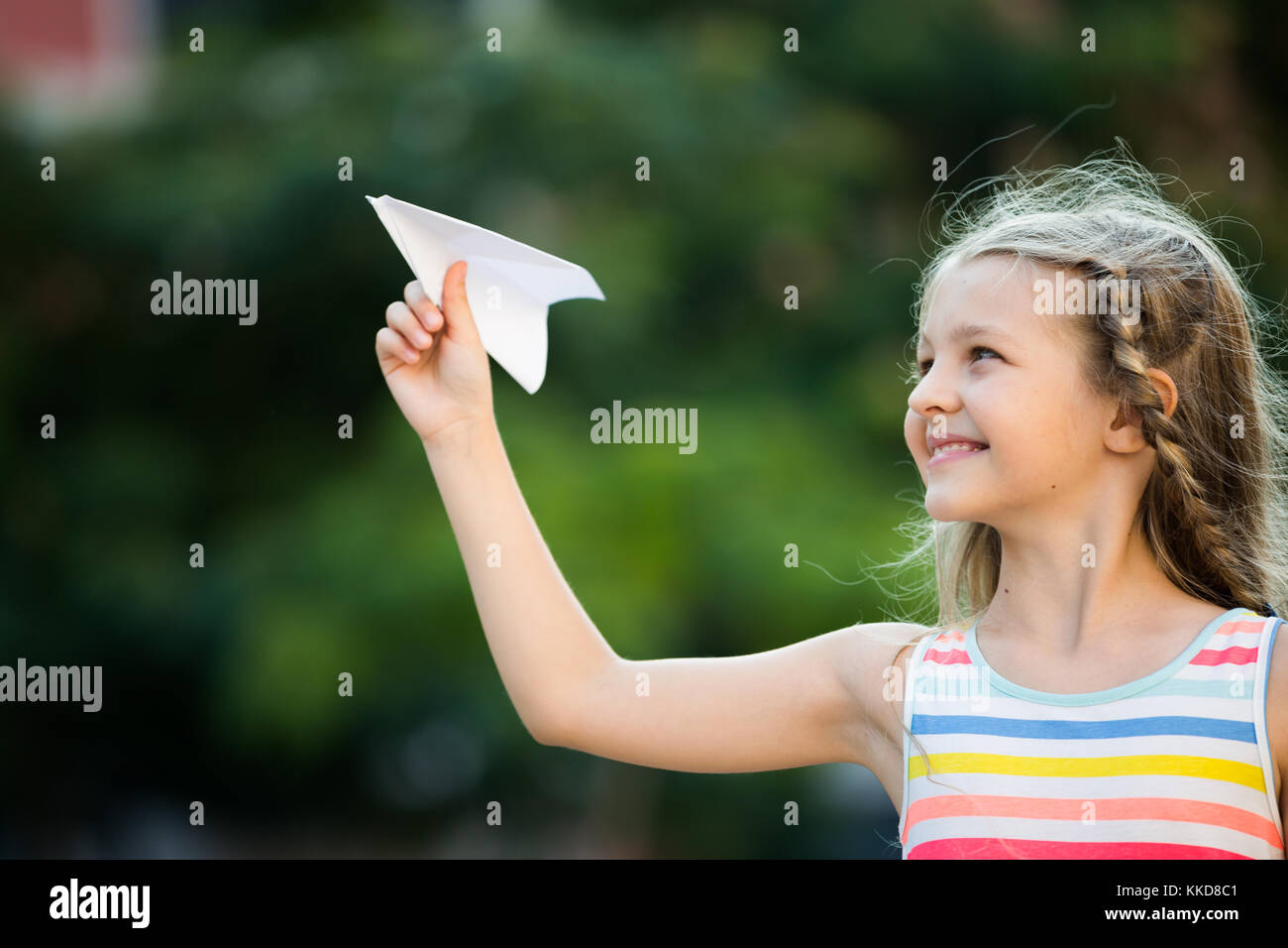 happy girl throwing simple paper airplane toy in air on sunny day Stock ...