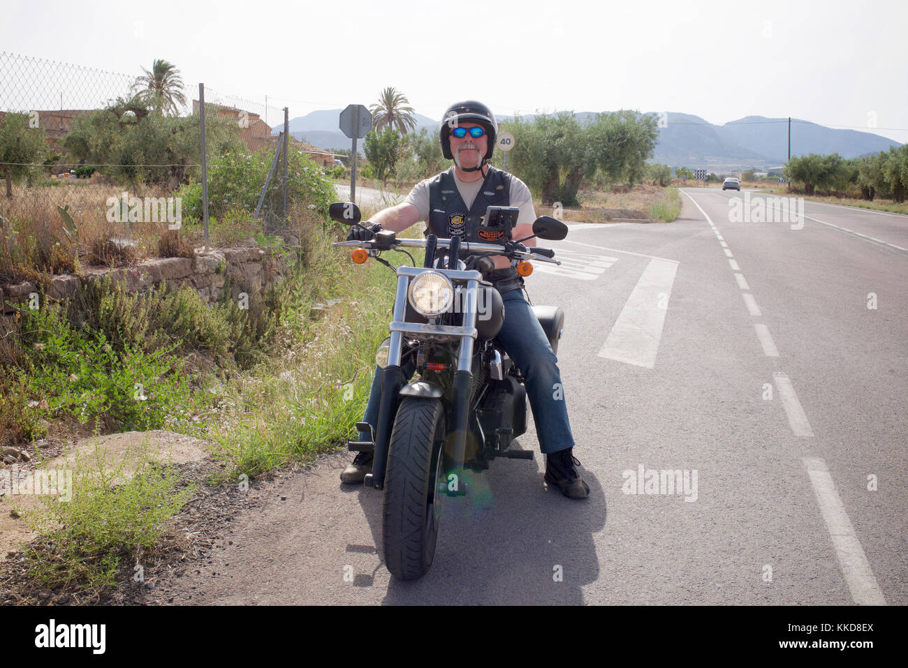 Man sitting on a Harley Davidson motorcycle by the roadside Stock Photo ...