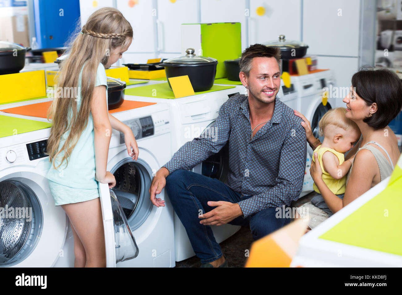 Cheerful family together choosing washing machine in shop of household ...