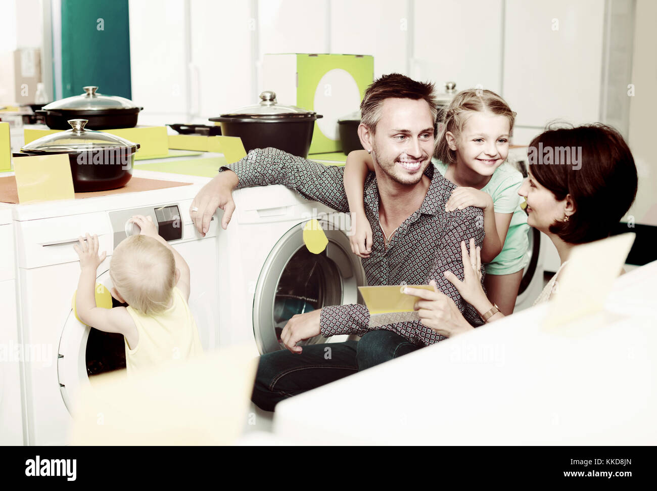 happy spanish parents with two kids choosing washing machine in home ...