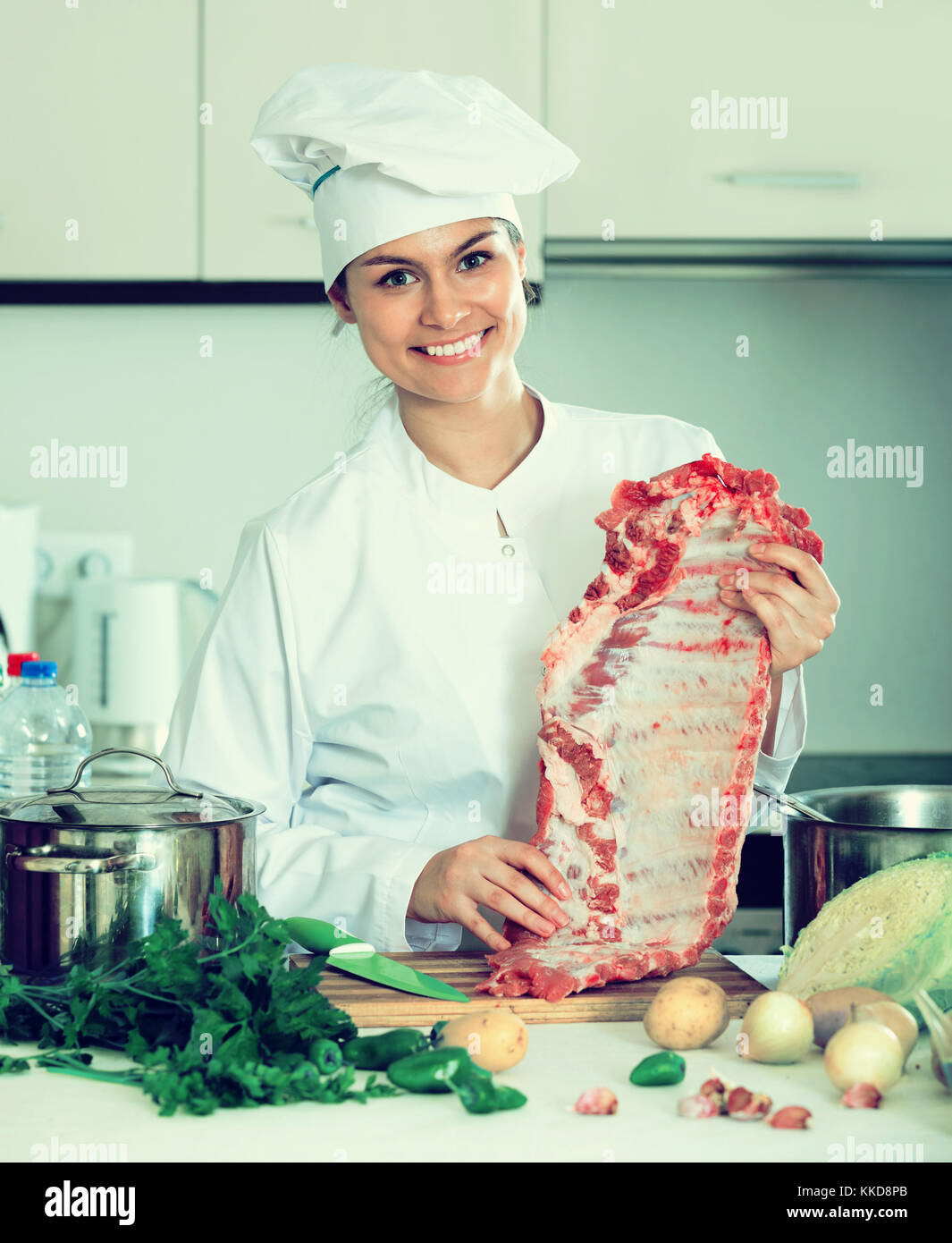 Portrait female chef working with pork ribs in kitchen at home Stock ...