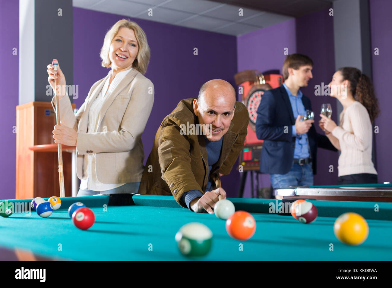 Positive middle class people having pool game and laughing in billiard ...