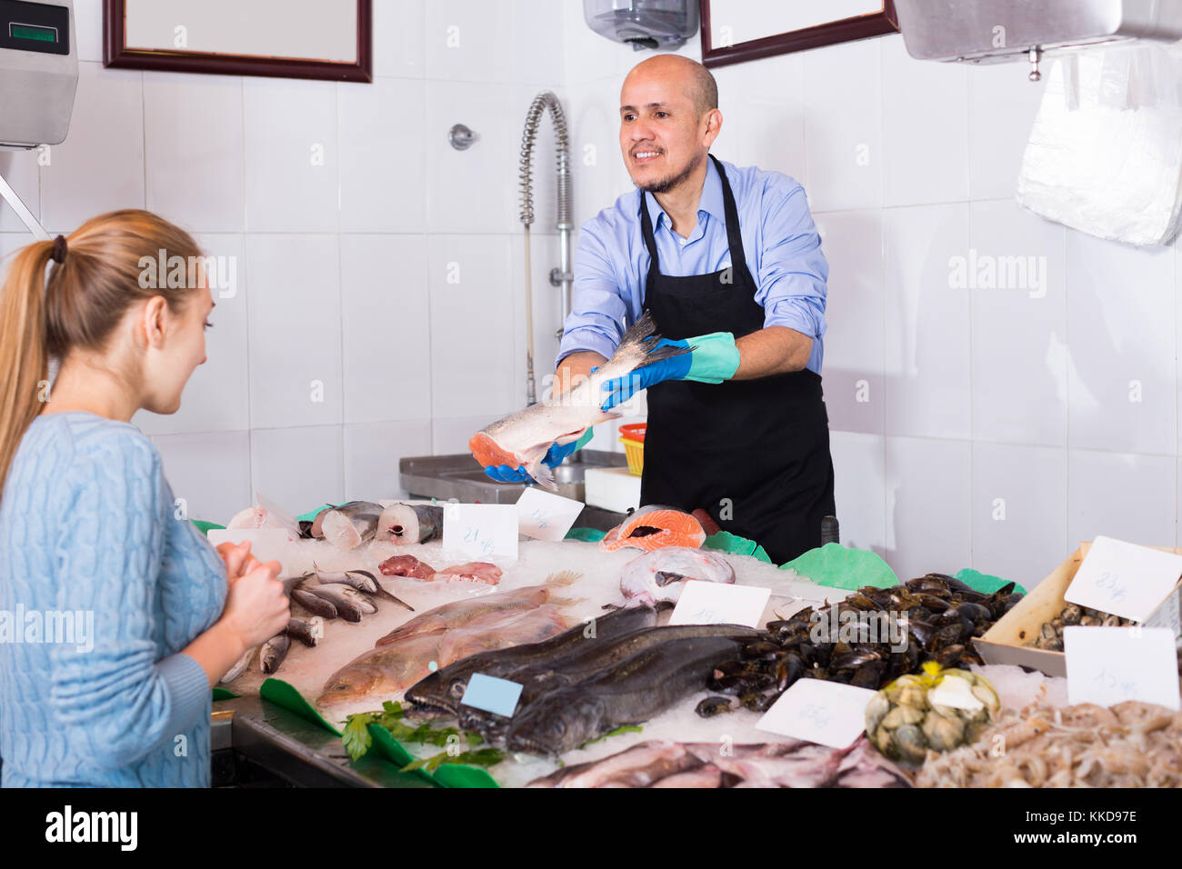 Blonde young woman in sweater selecting cooled fish at fishery Stock ...
