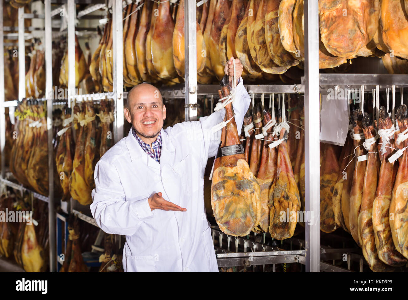 Mature butcher posing with the jamon joints at a meat factory Stock ...