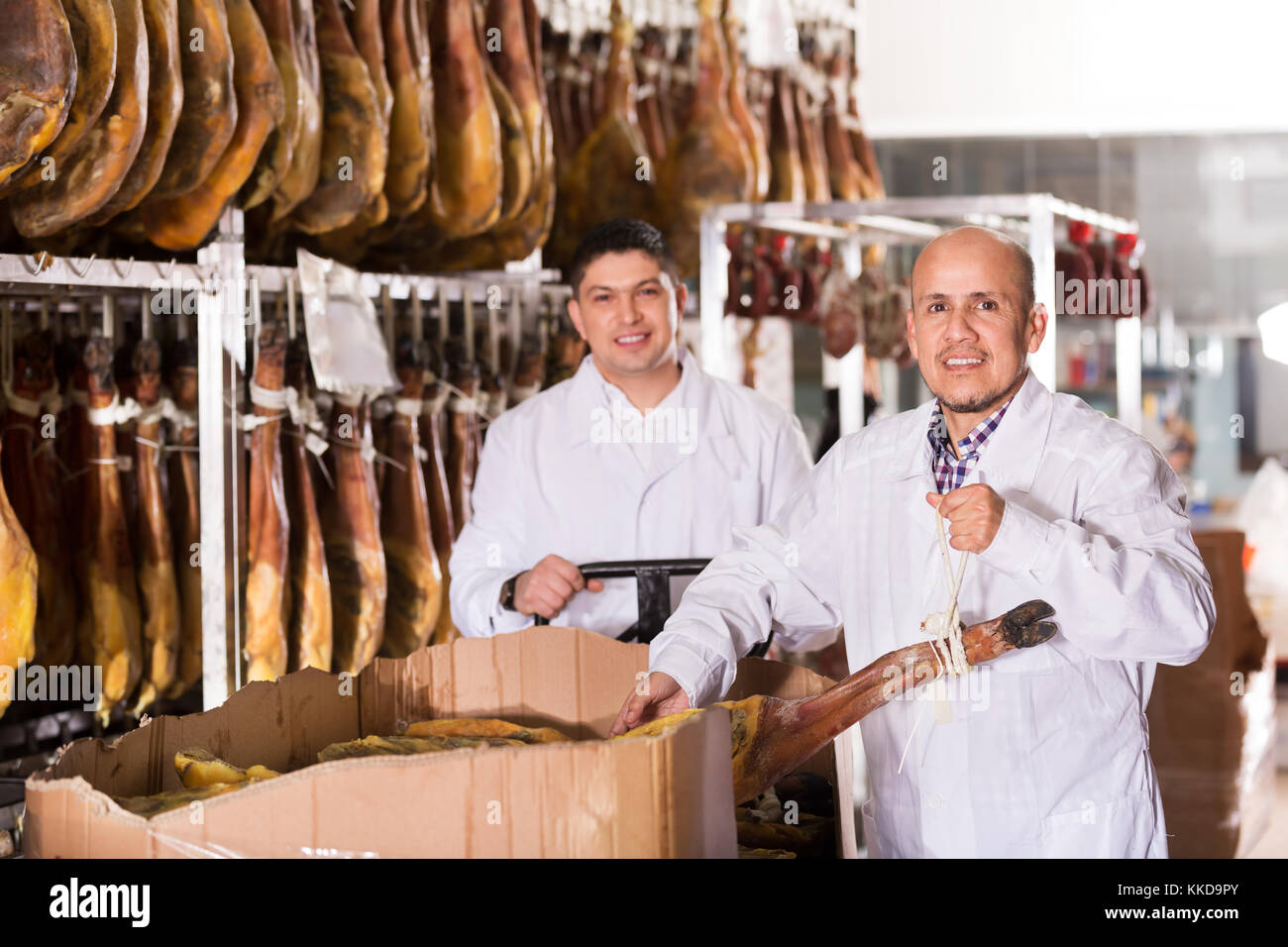 Mature butcher and assistant with jamon joints at a meat factory Stock ...