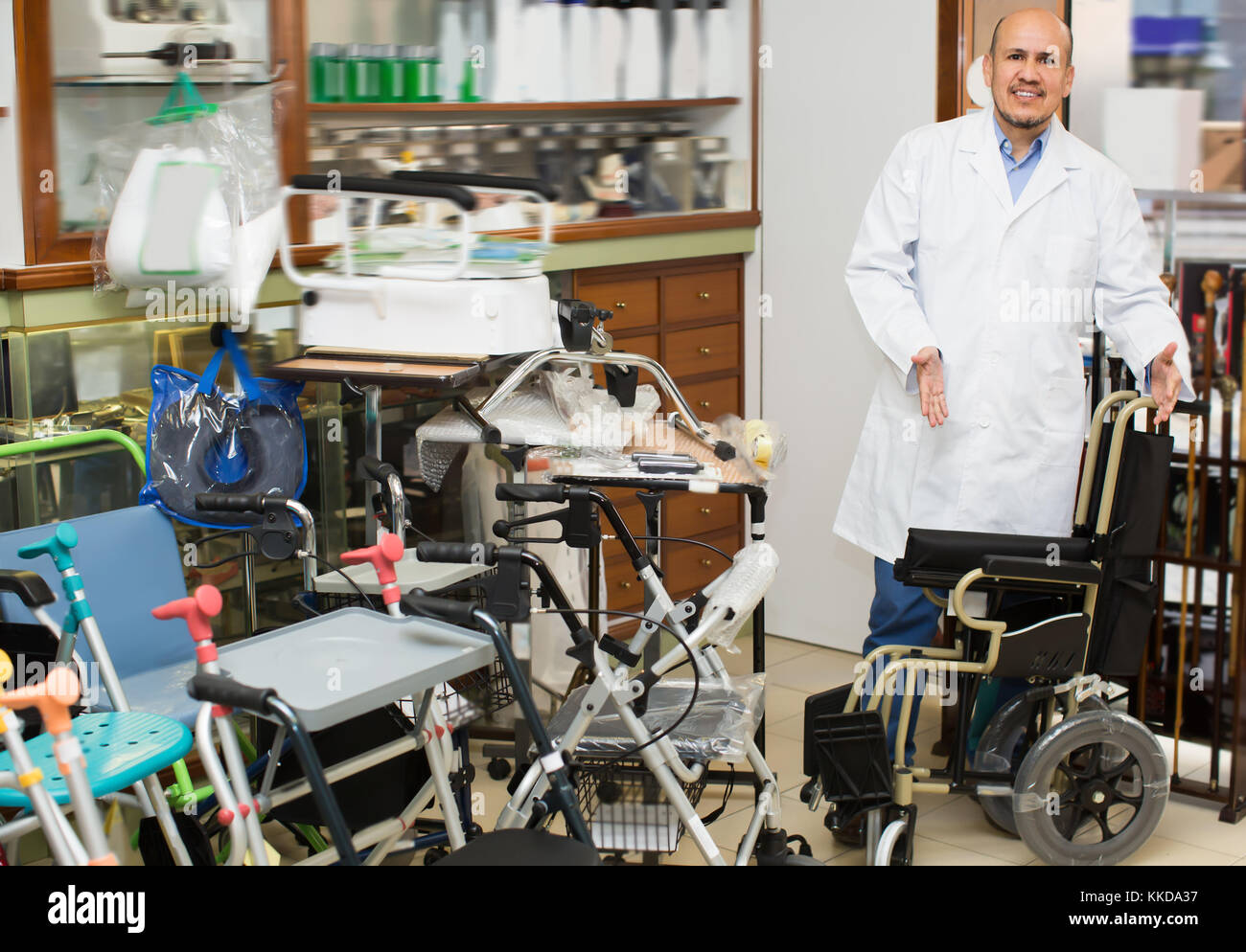 Elderly physician posing near display with orthopaedic equipment and ...