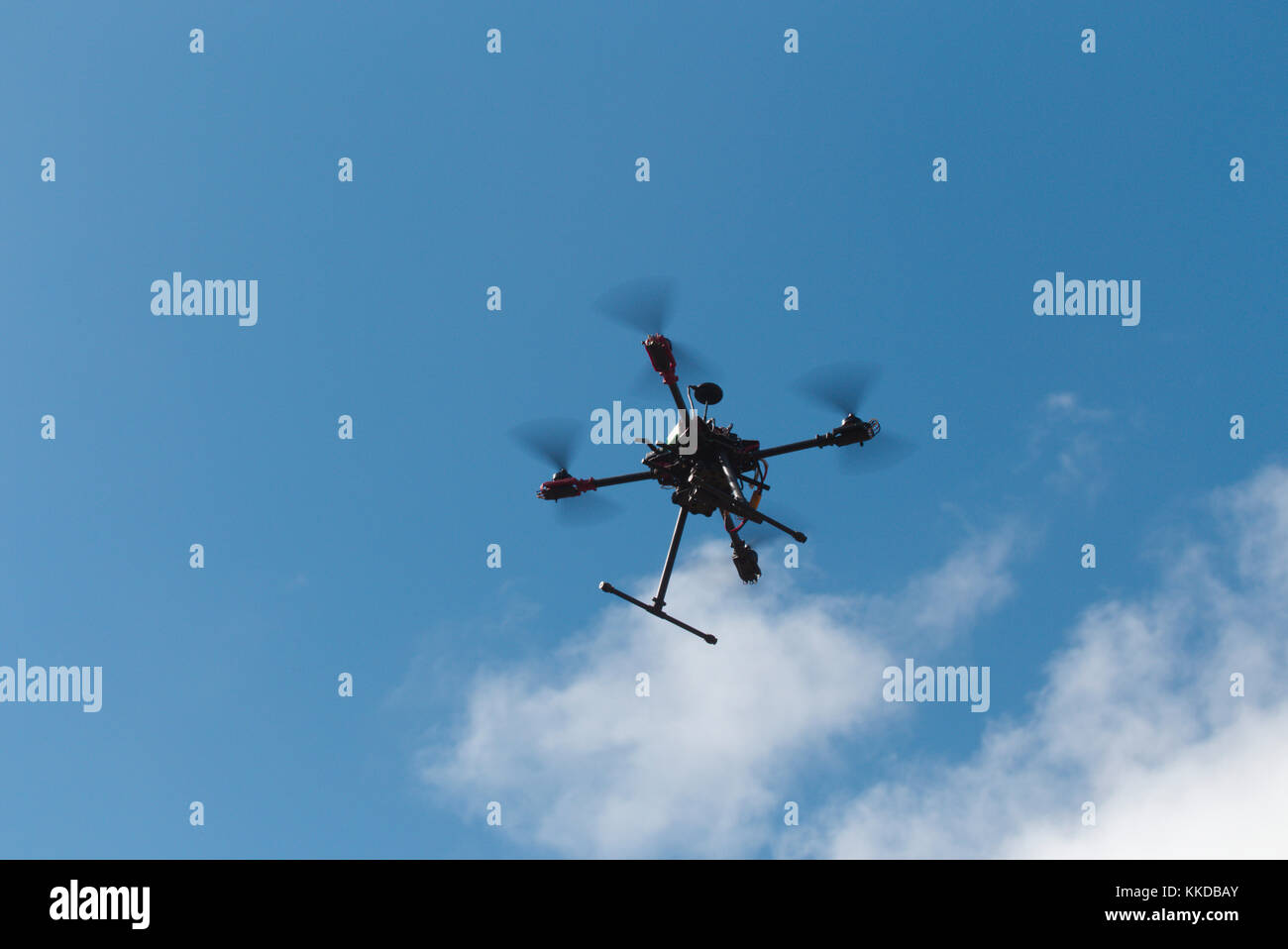 Aerial of custom built multirotor Quadcopter in flight against a blue ...
