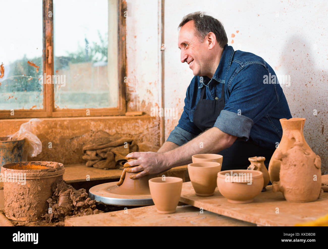 Elderly positive smiling master among the pottery at the workshop Stock ...
