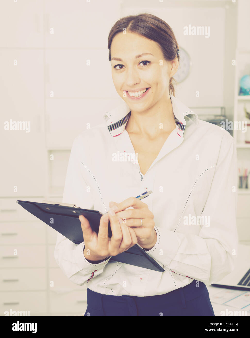 cheerful woman having clipboard in hands in company office indoors ...