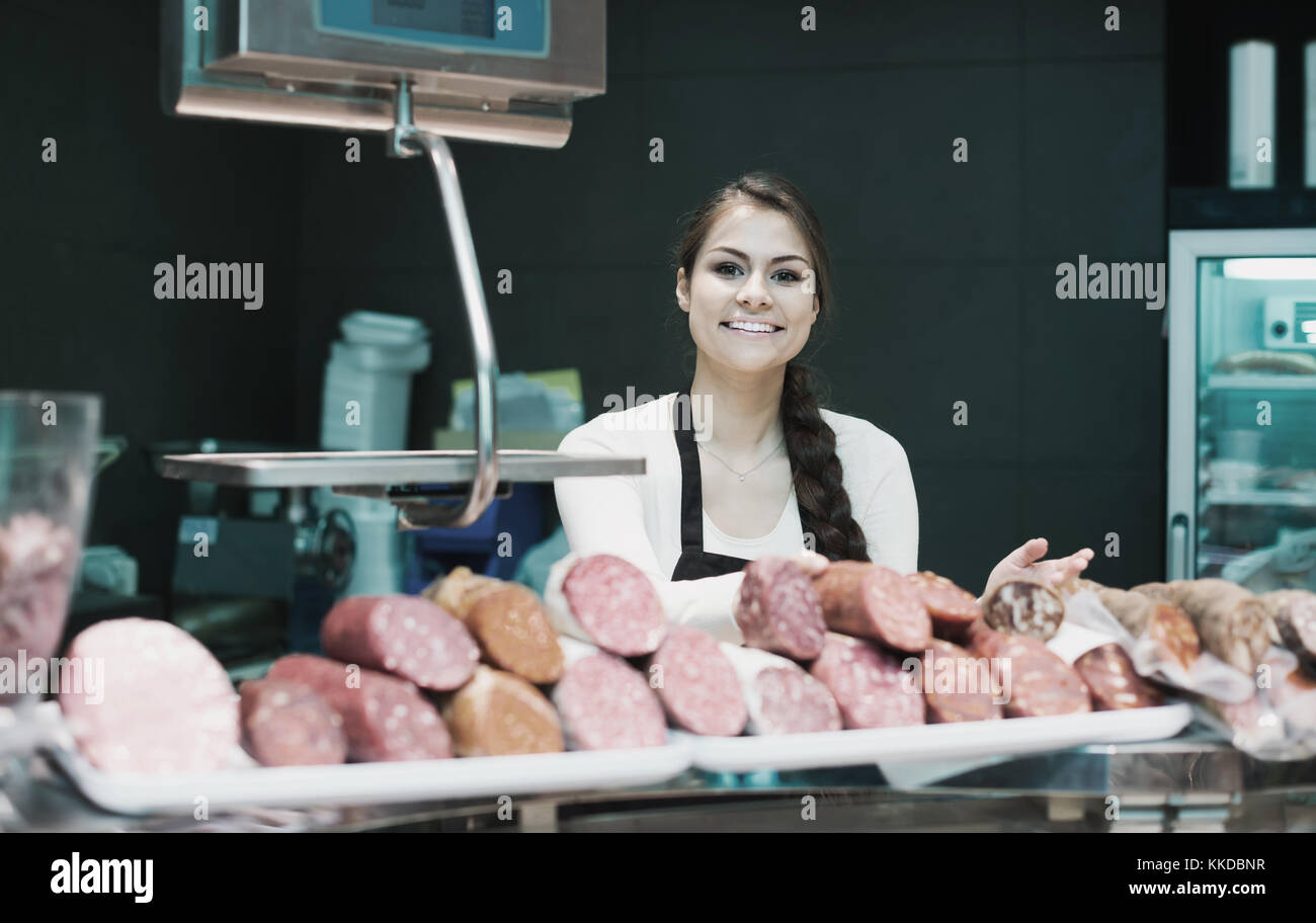 happy spanish female butcher with wurst and bologna in meat store ...