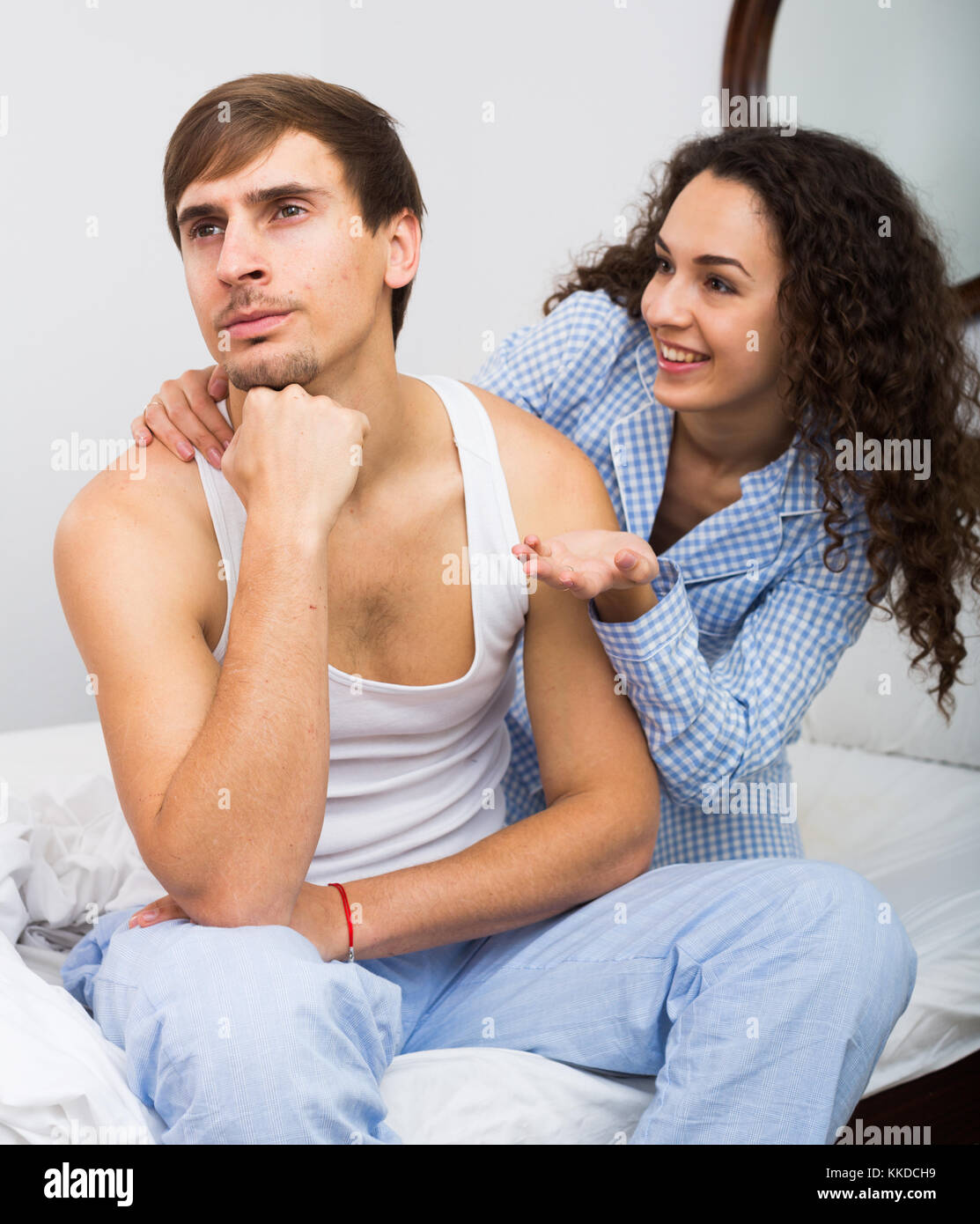 Brunette girl wheedling to offended young man sitting in bed Stock ...