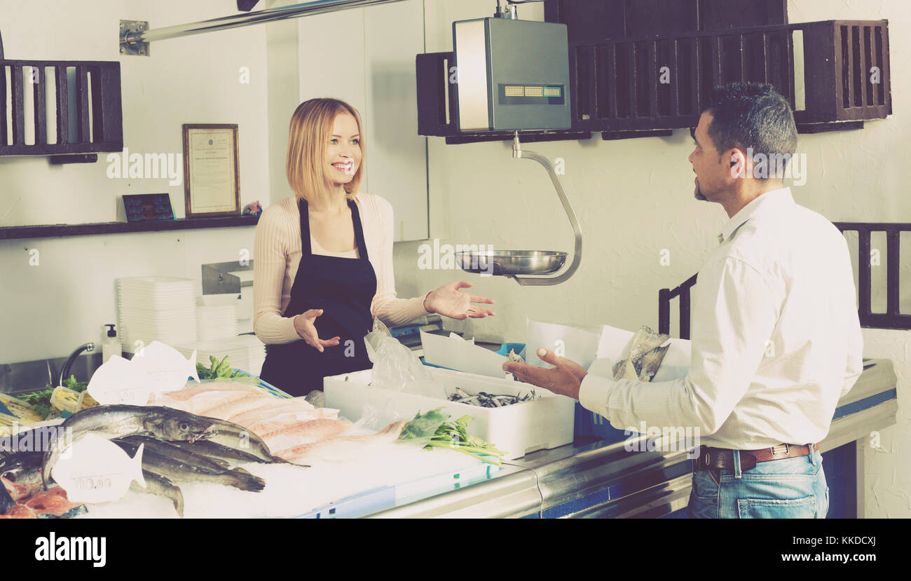 Ordinary male customer chosing cooled fish in supermarket and smiling ...