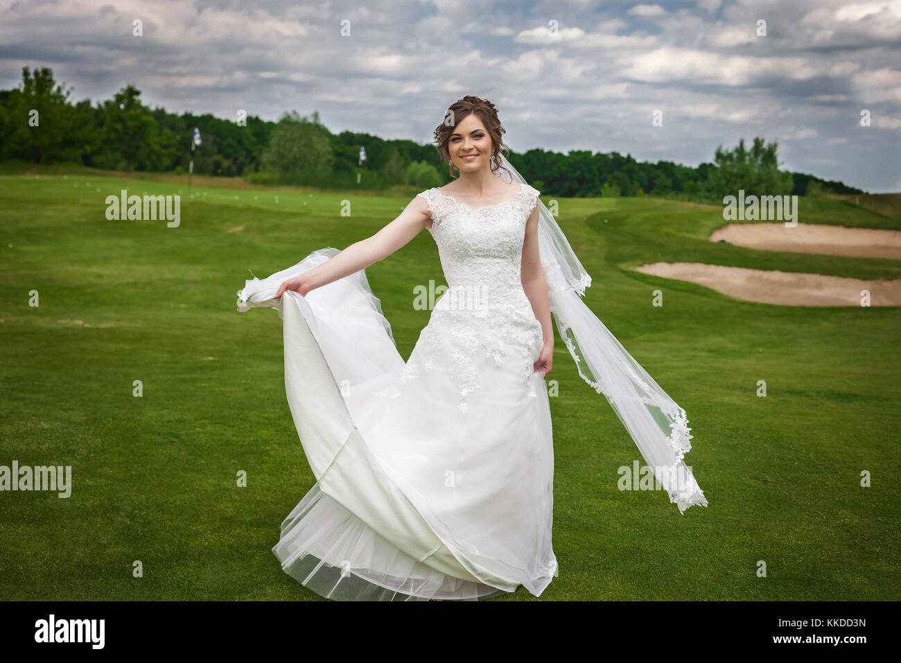 Attractive bride dancing on green golf course Stock Photo - Alamy
