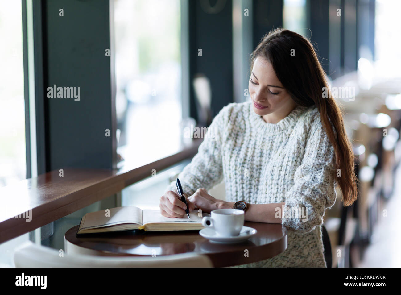 Young attractive woman writing diary in cafe Stock Photo - Alamy
