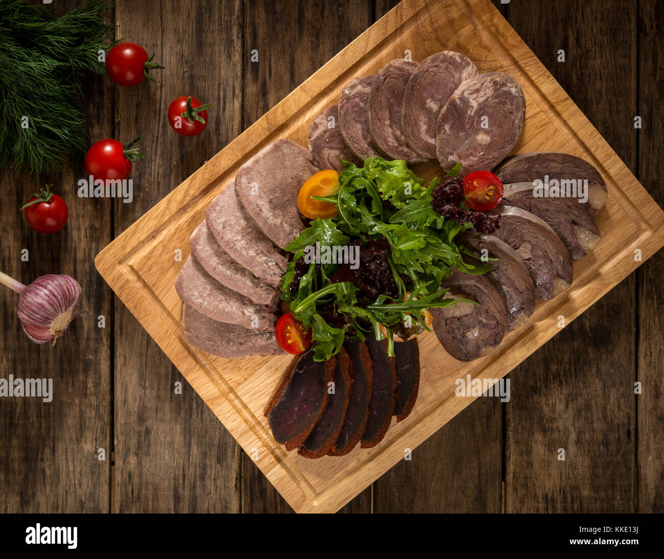 sliced meatloaf on a wooden tray and is decorated with vegetables, top ...