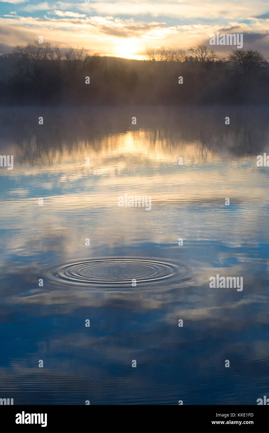 Sunrise and water ripple reflections on a lake in the village of ...