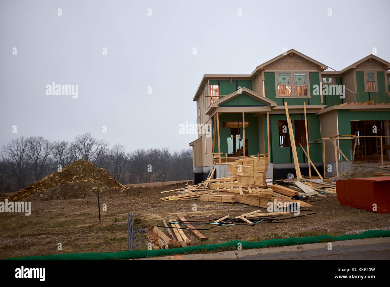 Unfinished new build country home with timber piled in front of it on a ...