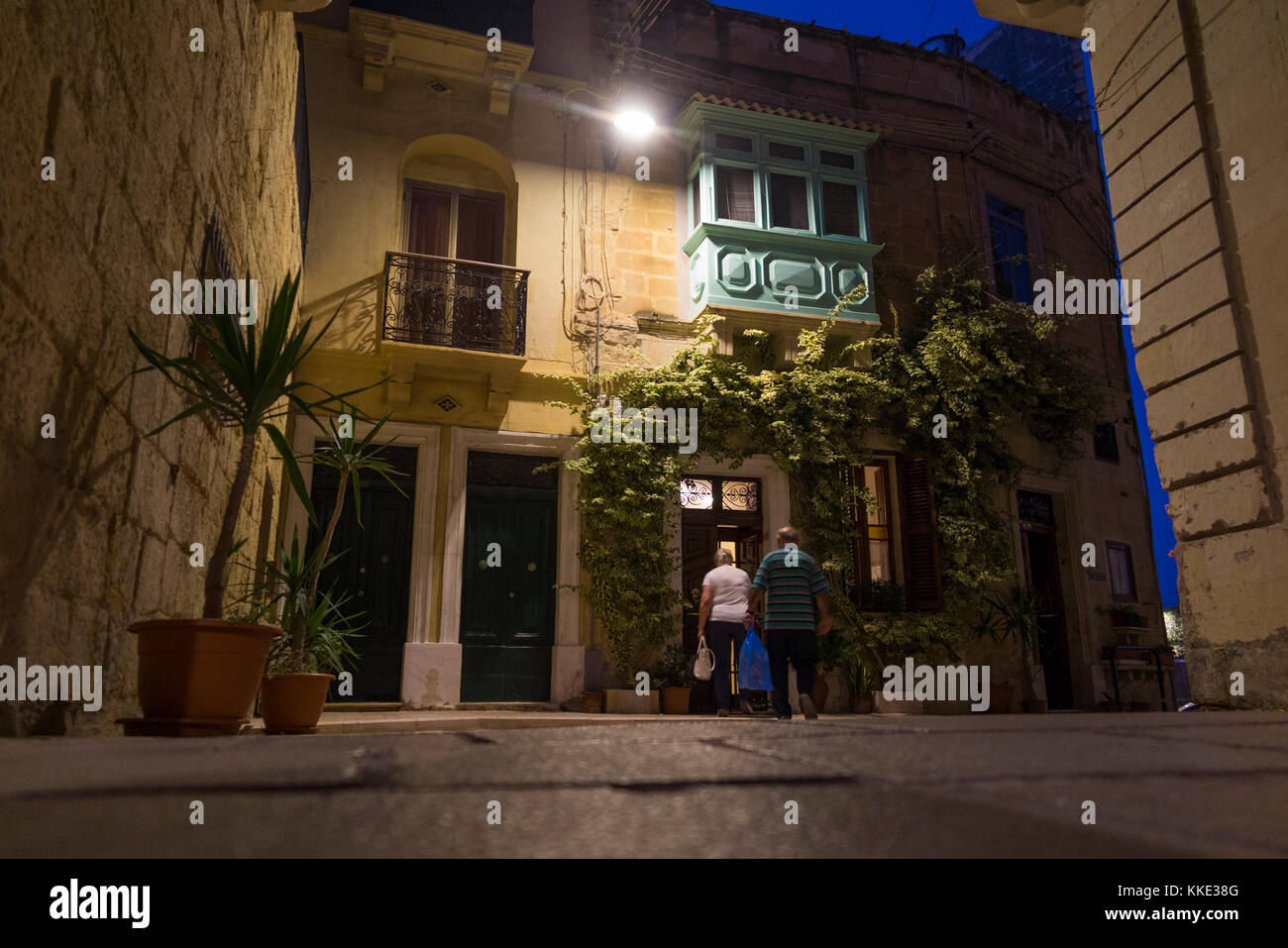 Couple / people come home in quiet streets & roads of Birgu, Malta, in ...
