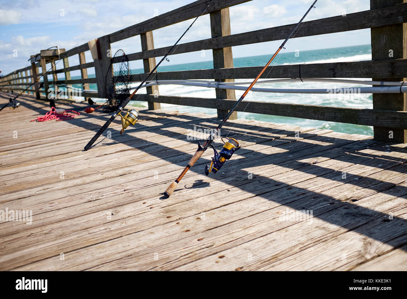Fishing rods leaning against the hand rail on a wooden marine jetty or ...