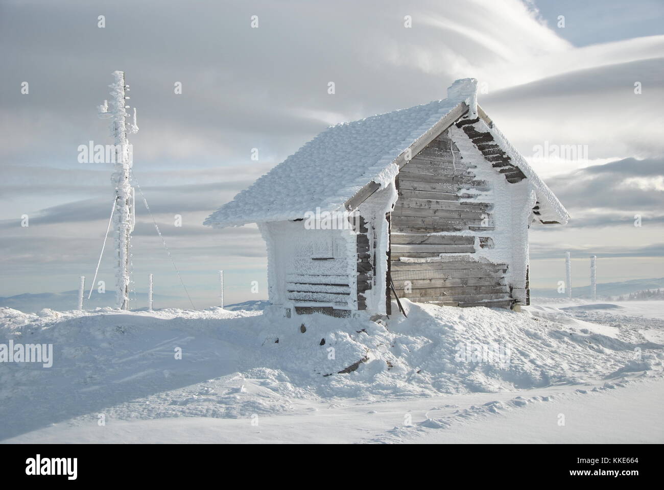 Small log house and frozen antenna on the top of the mountain in winter ...