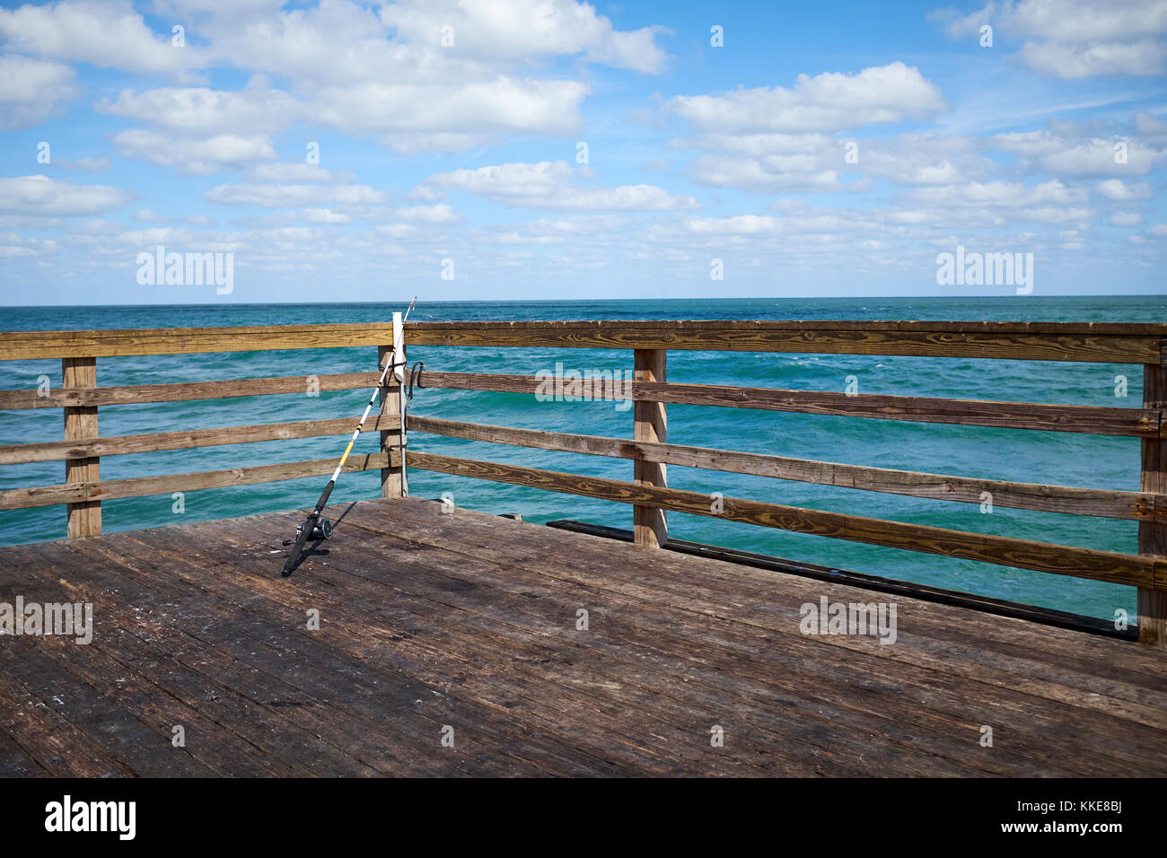 Old wooden dock with fishing rod balanced aainst the railing ...