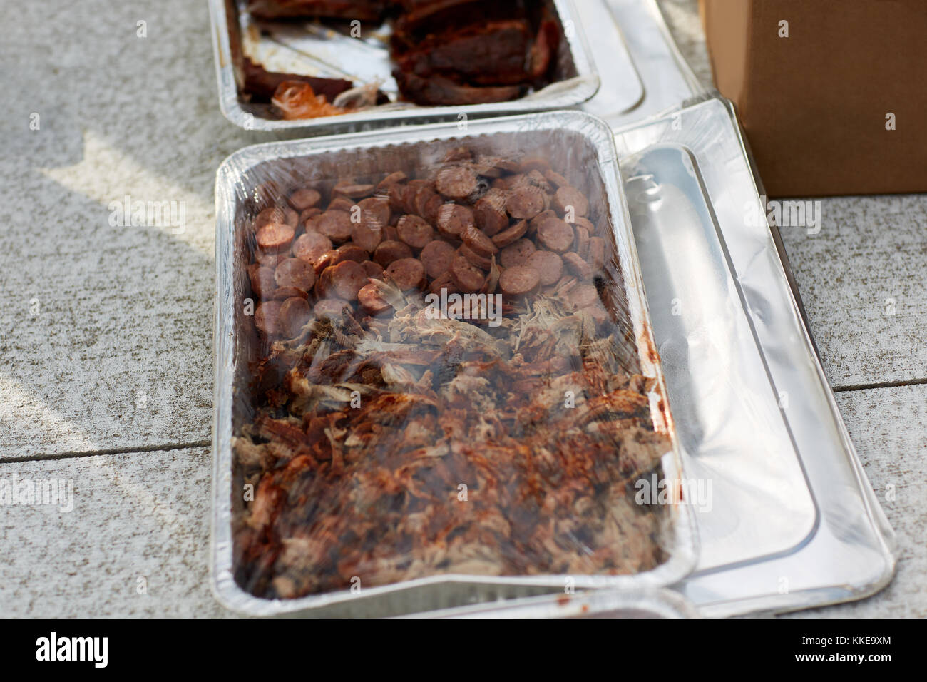 Freshly barbecued hot sliced meat in a metallic container on paving ...