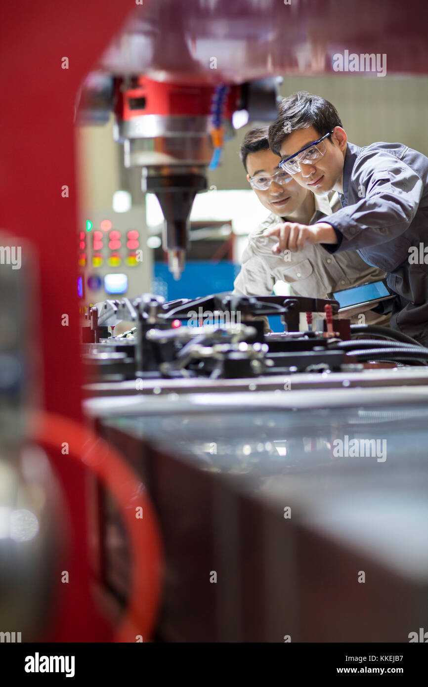 Young Chinese engineers checking machine in the factory Stock Photo - Alamy