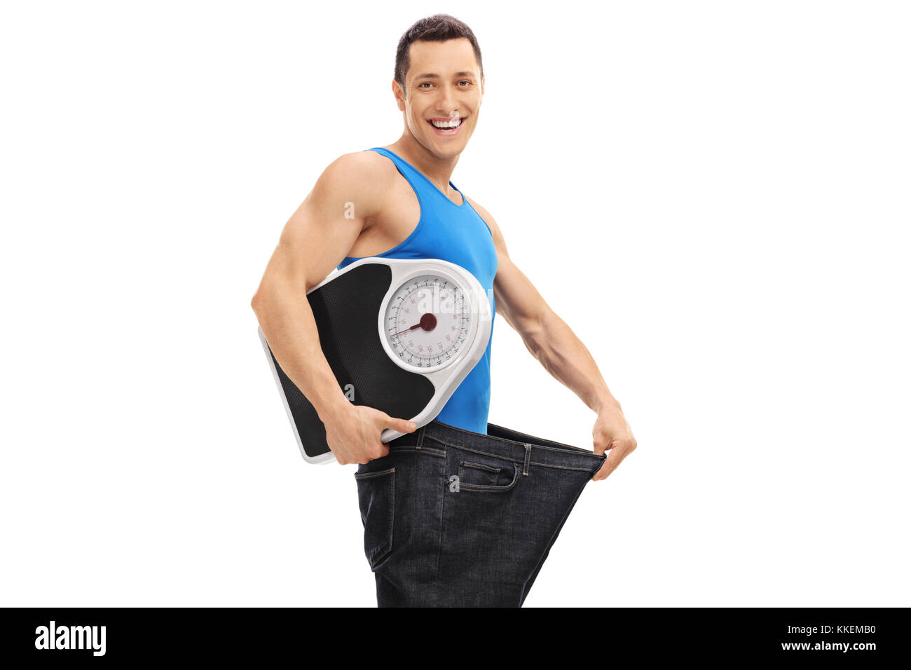 Guy in an oversized pair of jeans holding a weight scale isolated on ...