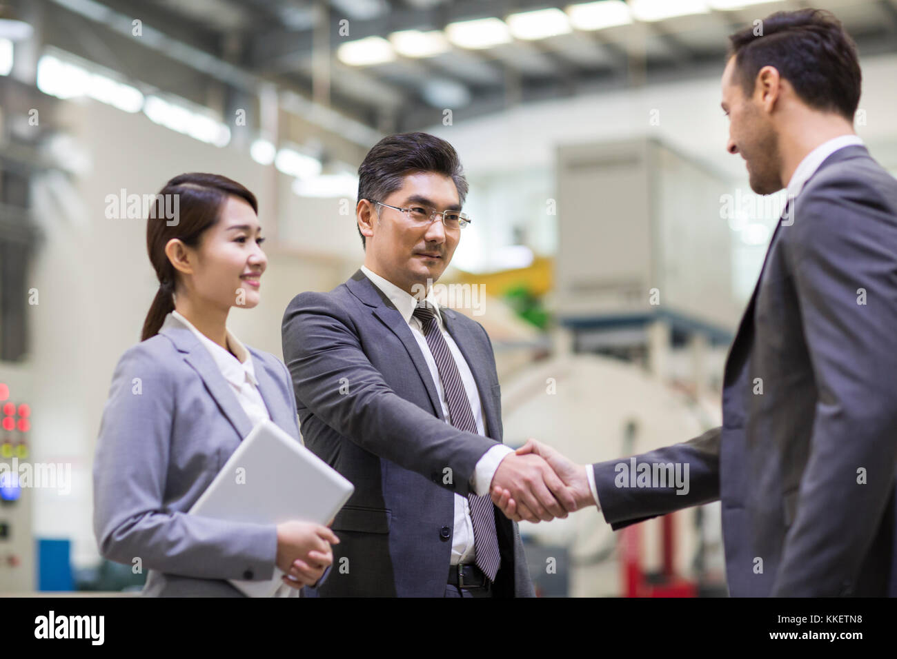 Business people shaking hands in the factory Stock Photo - Alamy