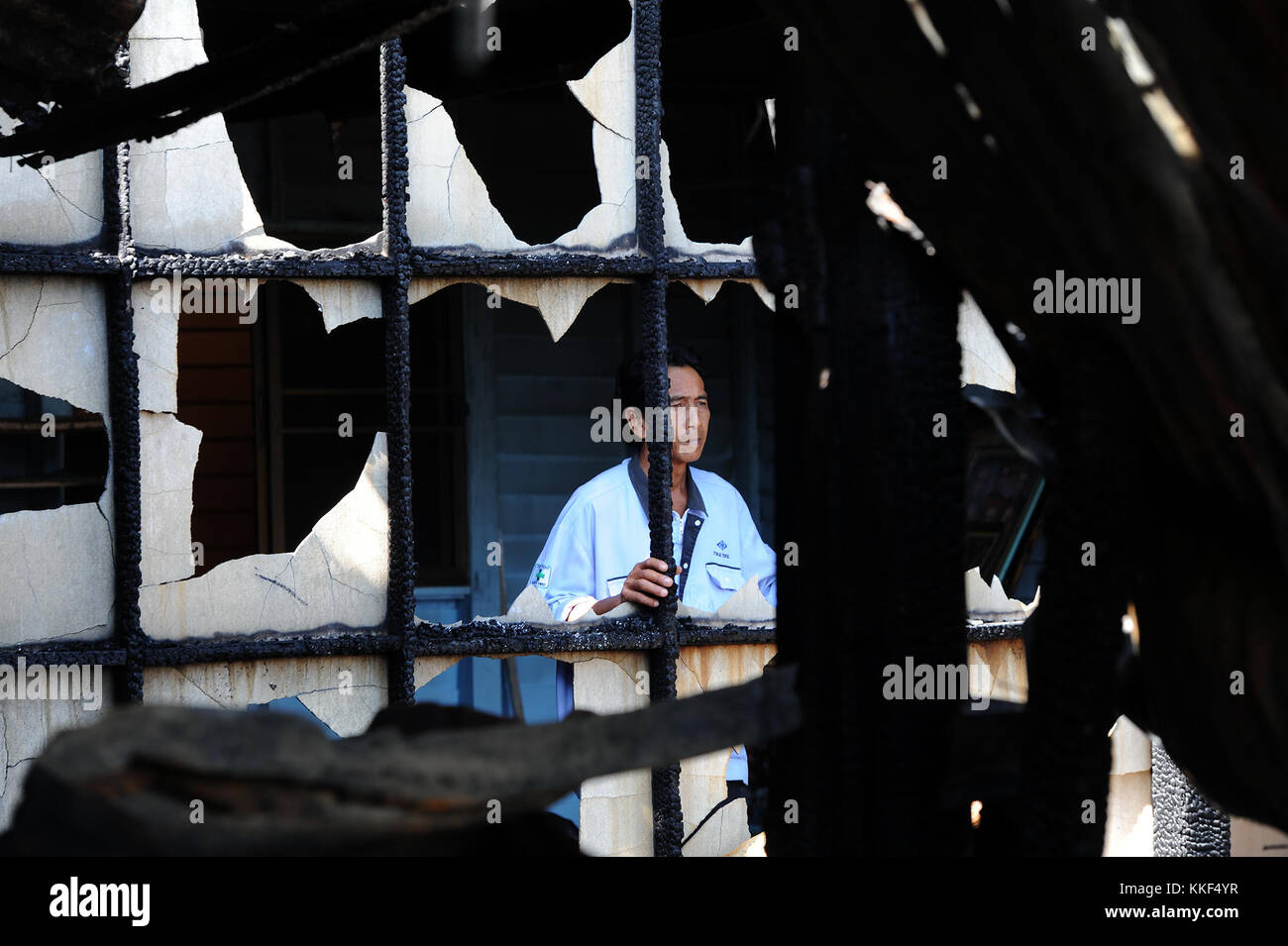 Bangkok, Thailand. 4th Dec, 2017. A man looks out from burnt window ...