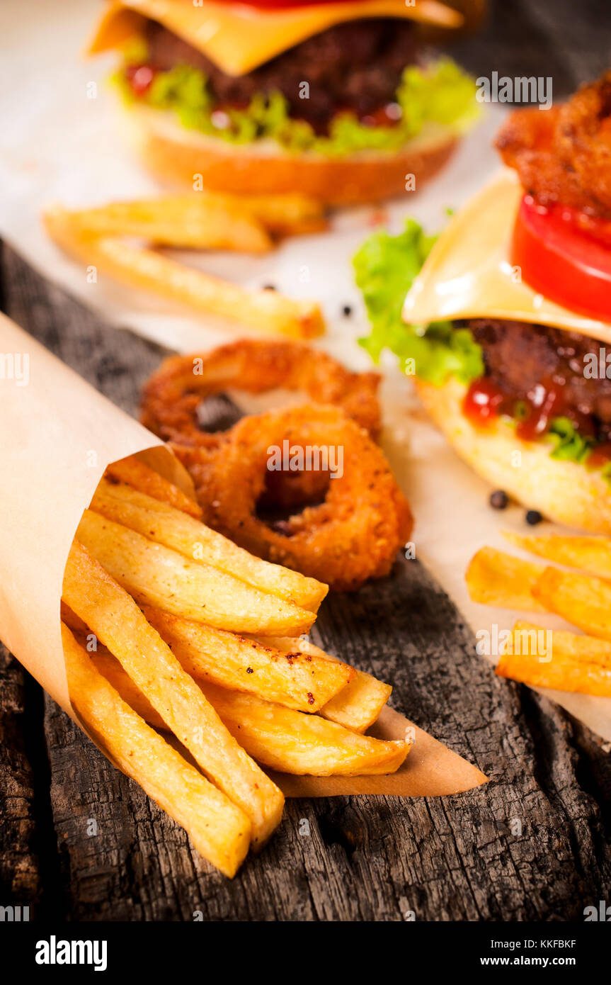 French fried in the paper cornet with cheeseburger in background Stock ...