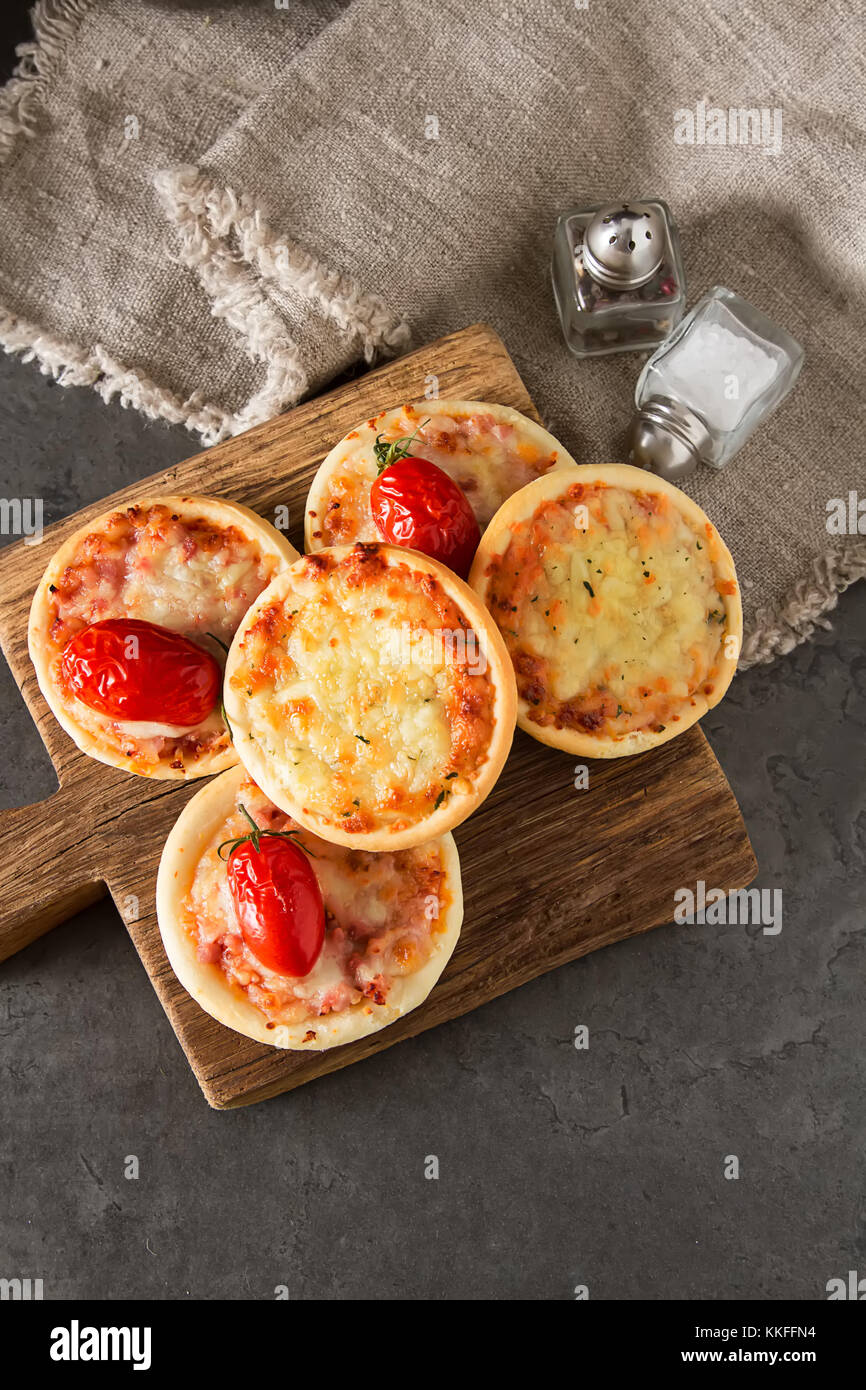Italian homemade mini pizza with cheese, tomatoes. Dark background ...
