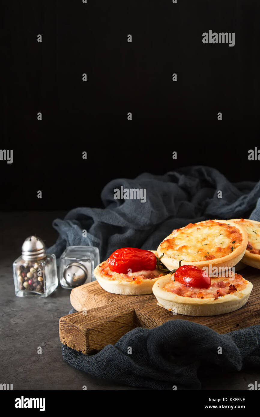 Italian homemade mini pizza with cheese, tomatoes. Dark background ...