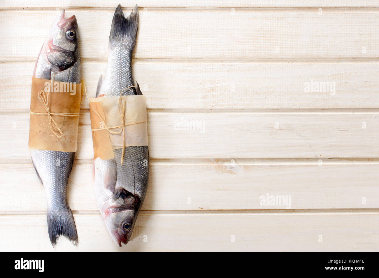 Bass fish head and tail from above on the wooden table with blank space ...