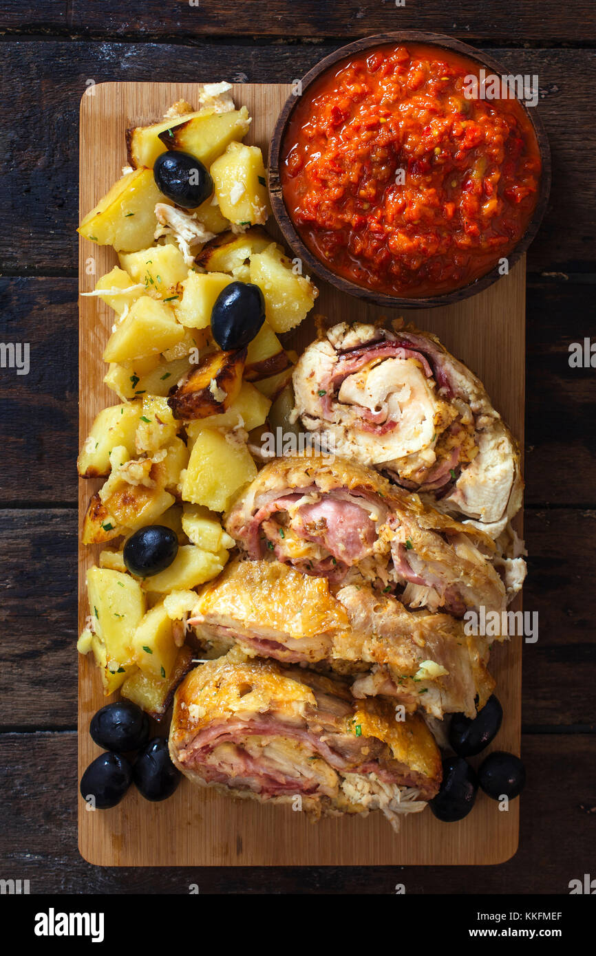Chicken roll and backed potatoes with ajvar salad on wooden background ...