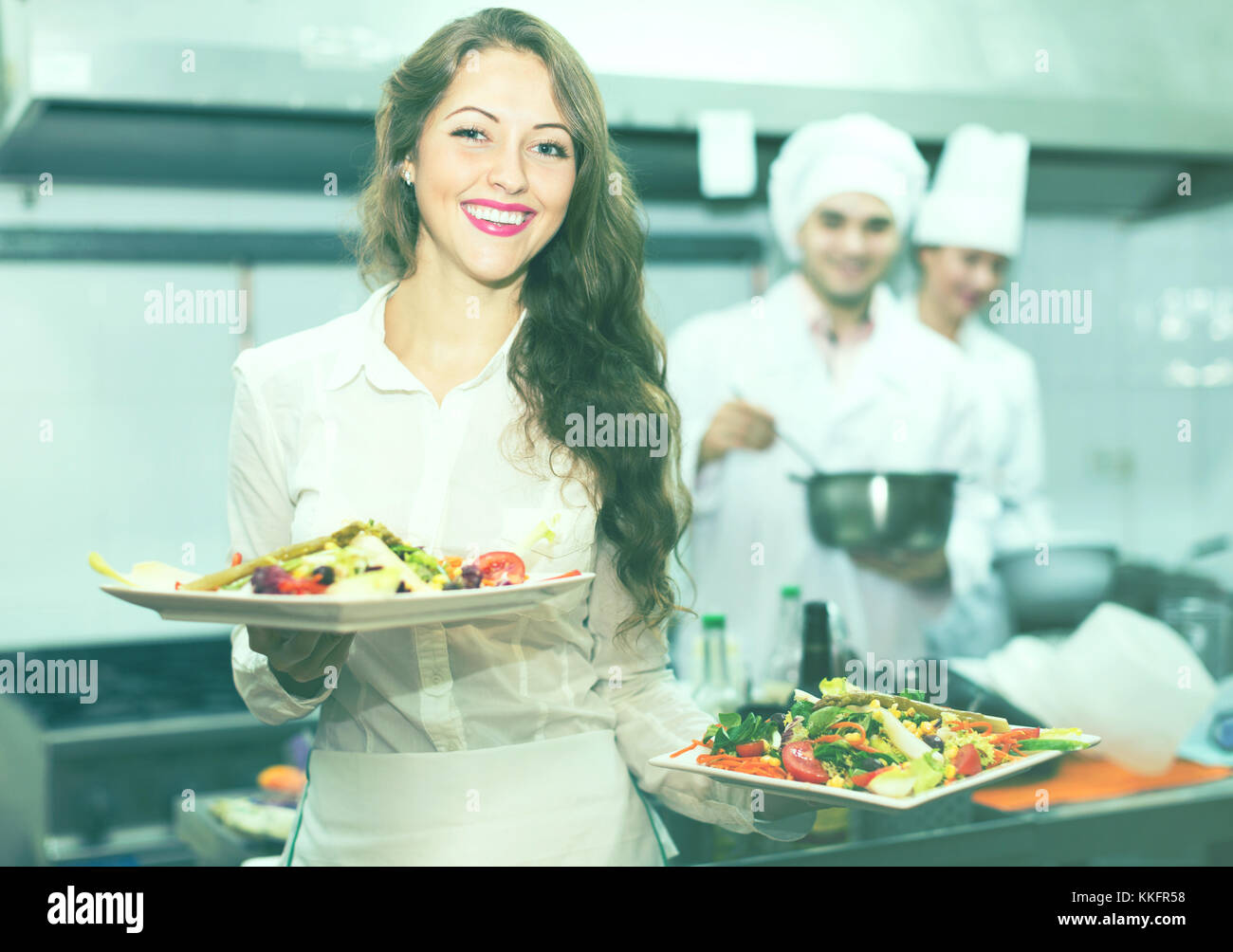 Team of chefs and young beautiful waiter at restaurant kitchen Stock ...