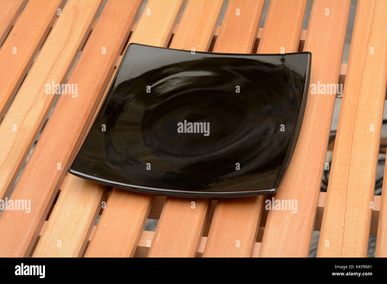 Black Color Slim Plate design on wooden table Stock Photo - Alamy