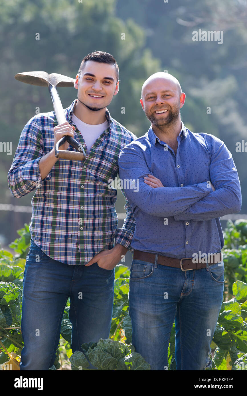 Two male farmers standing with spades at plantation Stock Photo - Alamy