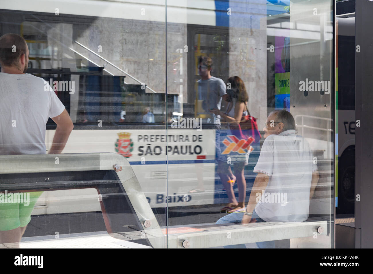 Street scenes. Two men wait at a bus stop as a bus arrives, Avenida ...