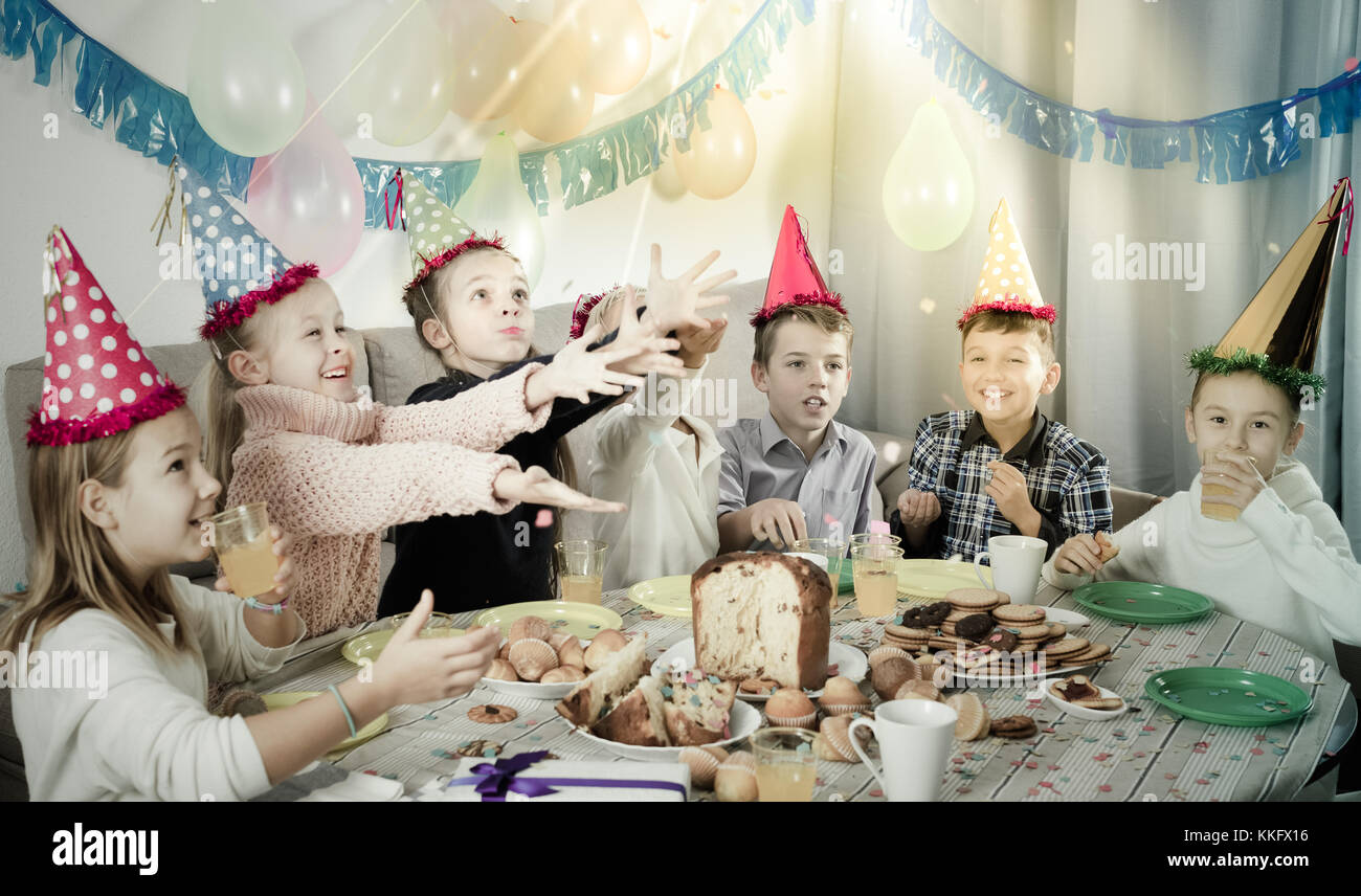 Smiling children happy to eat and drink at friend’s birthday party ...